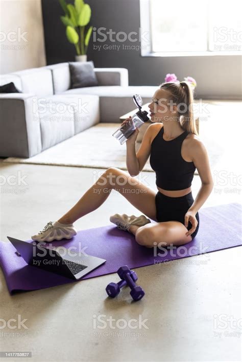 매트에 앉아서 집 거실에서 노트북을 사용하는 동안 물 한 병에서 마시는 여성에게 적합합니다 물에 대한 스톡 사진 및 기타 이미지 Istock