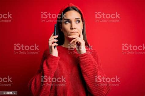 젊은 아름다운 갈색 머리 여자 는 질문에 대해 생각 하는 스마트 폰 심각한 얼굴에 이야기 하는 대화를 매우 혼란 스러운 아이디어