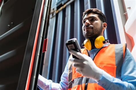 바코드 스캐너 검사관을 들고 안전 조끼를 입은 선착장 노동자 남자는 선적 야드에서 컨테이너의 품질을 검사합니다 물류 및 운송 글로벌 비즈니스 개념 수입 수출을 위한 화물