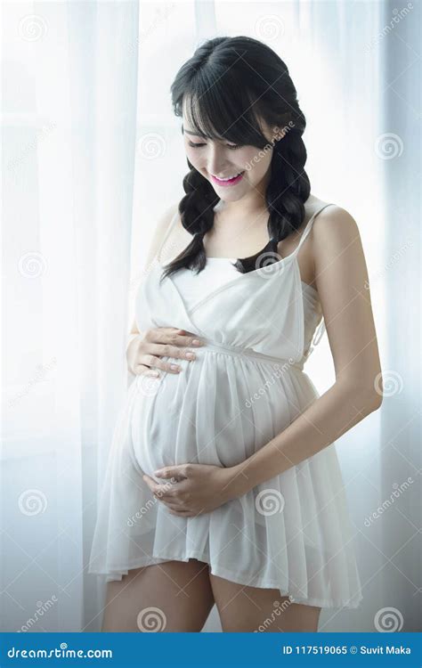 Young Pregnant Asian Woman Holds Her Hands On Her Swollen Belly Love