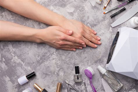 네일 케어 콘크리트 질감에 분홍색 부드러운 매니큐어에 의해 그려진 손톱을 만드는 아름다운 여성 손 전문 매니큐어 도구 세트 옆에 여성의 손 뷰티 케어 가꿔주기에 대한 스톡