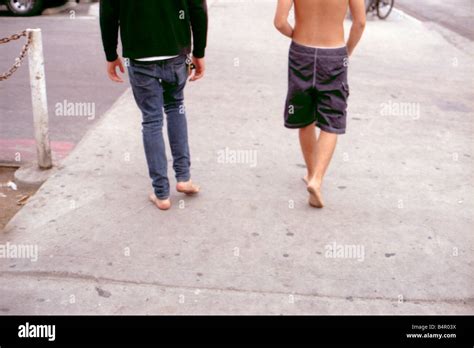 Two Teenage Boys Walking Down The Sidewalk Barefoot In Ocean Beach