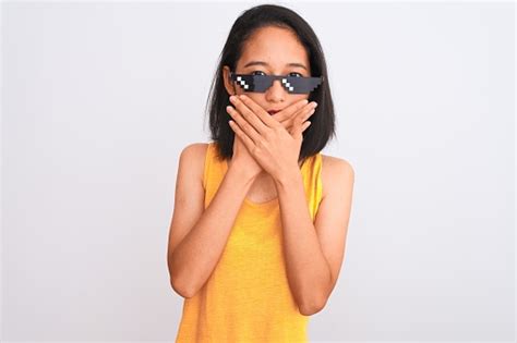 고립 된 흰색 배경 위에 깡패 생활 선글라스를 입고 젊은 아름다운 중국 여성은 실수로 손으로 입을 덮는 충격을 받았다 비밀 개념입니다 가리기에 대한 스톡 사진 및 기타