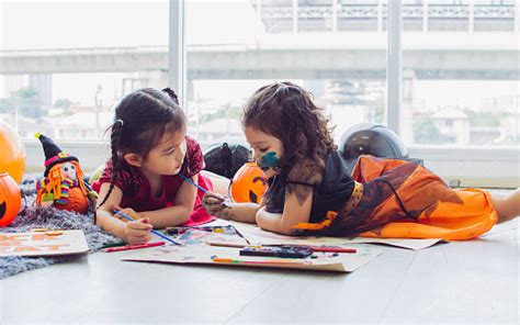 할로윈 파티를 축하하기 위해 마녀 의상을 입은 두 개의 작은 귀여운 백인 아시아 소녀 그림 행복 재미와 함께 거실바닥에 누워있는 동안 함께 그림 10월에 대한 스톡 사진 및