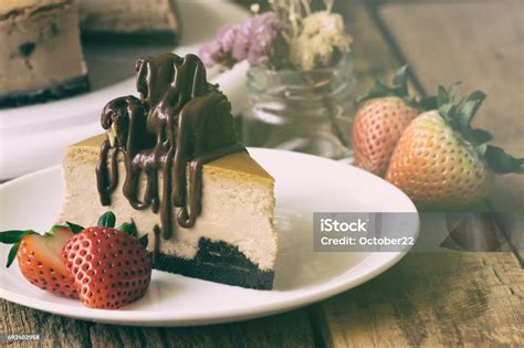소박한 나무 테이블에 수 제 초콜릿 치즈 케이크입니다 브라 우 니와 다크 초콜릿 소스 장식 딸기 토 핑 초콜릿 치즈 케이크를