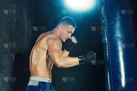 男性拳击手拳击在沙袋与戏剧性的尖锐照明