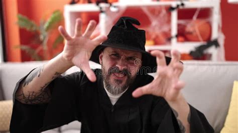 Young Bald Man Wearing Wizard Costume Doing Scare Gesture At Home Stock