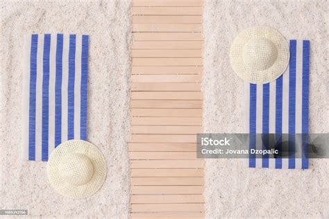 파란색과 흰색 줄무늬 수건과 밀짚 모자로 된 나무 길이 있는 모래 해변 해변에서 열대 여름 휴일의 최소 개념 0명에 대한 스톡