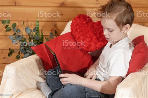 발렌타인 데이 어린이 또는 어린이 빨간 심장 베개와 노트북에 가제트 작업 또는 비디오 채팅 귀여운 어린 소년 발렌타인 데이를 축하하거나 엽서 축하 밸런타인데이에 대한 스톡