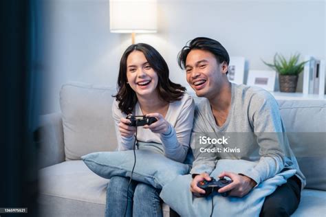 아시아 의 젊은 남자와 여자 부부는 집에서 함께 게임을 즐길 수 있습니다 매력적인 재미 남성과 여성 친구는 행복 느낌 거실에서 소파에 앉아 함께 집에서 조이스틱 게임을 재생