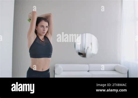 A Young Girl Raises Her Arms With Dumbbells From Behind Her Head Doing Triceps Exercises