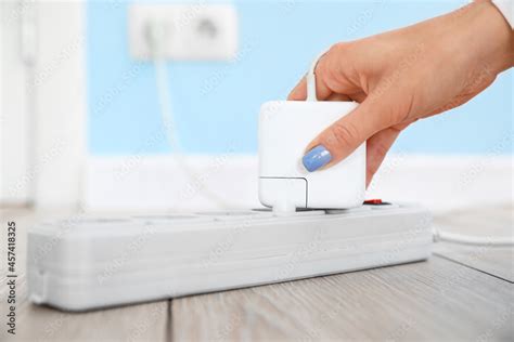 Woman Inserting Plug Into Extension Cord In Room Stock Photo Adobe Stock