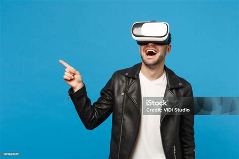 검은 자 켓 흰색 T 셔츠에서 세련 된 젊은 면이 없는 남자 헤드셋 파란색 벽 배경 스튜디오 초상화에 고립 된 가상 Vr 현실 사람들의 감정 라이프 스타일 개념입니다 복사