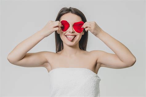 흰색 바탕에 서 있는 젊은 예쁜 여자 그 동안 그녀의 눈을 덮고 빨간 꽃잎으로 그녀의 팔을 올렸다 혀를 보여줍니다 가꿔주기에 대한 스톡 사진 및 기타 이미지 Istock