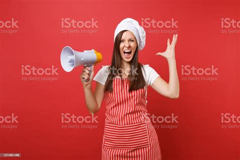 주부 여성 요리사 요리사 또는 줄무늬 앞치마 T셔츠 모자 요리사 모자 빨간 벽 배경에 고립 된 베이커 확성기 비명 소리 충격된 여자 할인 판매를 발표 했다 복사 공간 개념을