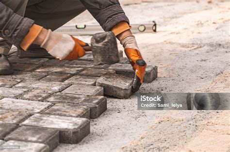 포장 슬래브를 클로즈업합니다 노면 건설 보도 수리 돌 포장 슬래브를 놓는 노동자 도시 공원 정원에 타일을 놓습니다 수동 고정 테셀레이션 포장 슬래브 마당의 차도에 대한 스톡