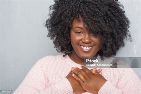 젊은 아프리카계 미국인 플러스 크기 여자 겨울 닫힌된 눈과 얼굴에 감사 제스처와 함께 가슴에 손을 스웨터와 미소를 입고 회색