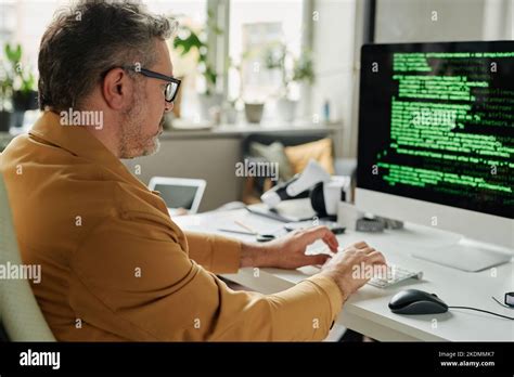 Side View Of Mature Serious Male IT Engineer Typing On Computer