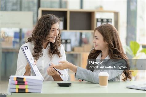 사무실에서 작업 문서를 가지고 회의 테이블에서 랩톱 컴퓨터를 사용하여 일하는 두 명의 쾌활한 사업가 부동산 프로젝트를 논의하기 위해 회의를 위한 비즈니스 동료 2명에 대한