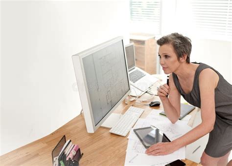 Mature Woman Architect And Reading With Computer Screen And Ideas With Review Floor Plan Or