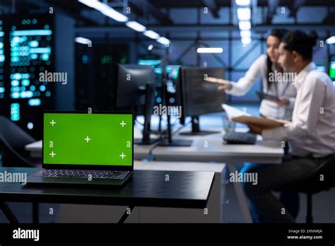Close Up Of Green Screen Laptop In Data Center With Workers Checking Emergency Procedures