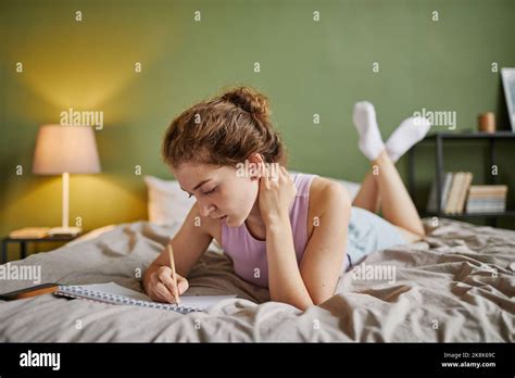 Girl Making Notes In Notebook While Lying In Her Bed In Bedroom Stock Photo Alamy