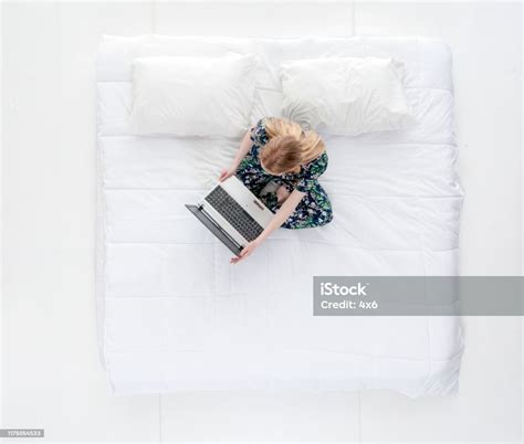 직접 위의 보기 전체 길이 2029 세 성인 아름 다운 백인 여성 젊은 여성의 한 사람 침실에서 흰색 배경 앞에 앉아 잠옷을 입고 누가 작업 하 고 노트북 컴퓨터를 사용 하