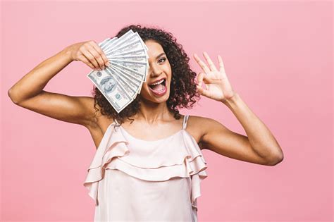 리치 소녀 머니 우승자 돈을 들고 드레스에 아름 다운 아프리카계 미국인 여자를 놀라게 하 고 분홍색 배경에 고립 된 카메라를