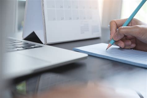 비즈니스 우먼의 클로즈업 종이 메모장에 메모를 작성 직장에서 사무실 테이블에 데스크톱 달력 및 노트북 컴퓨터와 개인 주최자에 의제를 만들기 검색에 대한 스톡 사진 및 기타