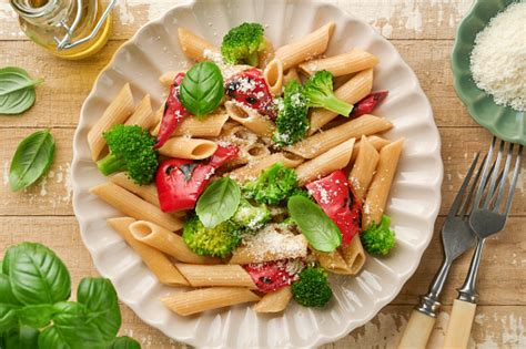 브로콜리와 빨간 구운 피망을 곁들인 통곡물 파스타 펜네와 밝은 나무로 된 소박한 배경 테이블 비건 파스타 전통 이탈리아 요리 플랫 레이 공간을 복사합니다 0명에 대한 스톡