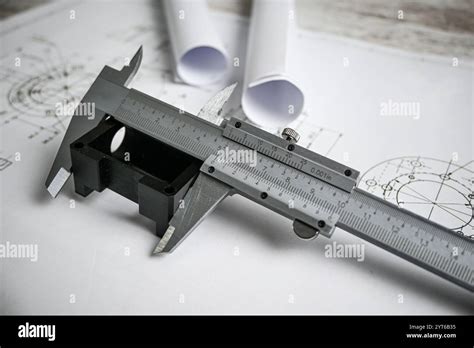 Caliper Measuring A Plastic Component On Top Of Technical Drawing Engineering And Quality
