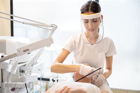 뷰티 살롱에서 여성 얼굴에 회춘 치료를하는 얼굴 방패를 착용 한 미용사 20 24세에 대한 스톡 사진 및 기타 이미지 20