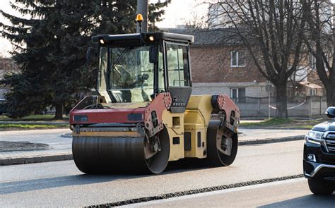 무거운 진동 롤러 압축기아스팔트 도로 롤러는 도로 건설 현장의 도로에 새로운 뜨거운 아스팔트를 누릅니다 아스팔트 포장 작업에서 무거운 진동 롤러 복구 거리에 대한 스톡 사진