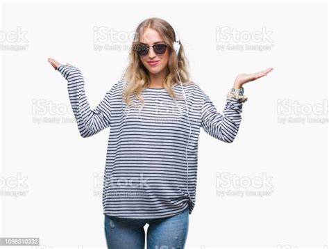 아름 다운 젊은 금발 여자 팔과 손을 제기와 격리 된 배경 우 둔 하 고 혼란 스 러 워 식 이상의 헤드폰과 선글라스 입고 의심 개념입니다 감정에 대한 스톡 사진 및 기타