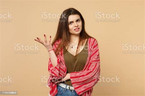 캐주얼 한 옷 카메라를 찾고에 자극 젊은 여자의 초상화 스튜디오에서 파스텔 베이 지 벽 배경에 고립 된 손을 확산 사람들은