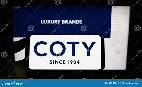 Person Holding Smartphone With Logo Of Us Beauty Company Coty Inc On