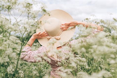 분홍색 드레스를 입은 날씬한 젊은 여성과 야생화 사이에서 여름 초원을 걷는 밀짚 모자 뒷모습 여름 아름다움 느린 생활 개념 30