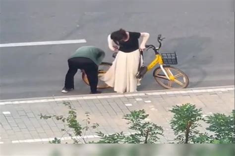 女子骑单车裙子被卡，热心大爷帮忙解困。