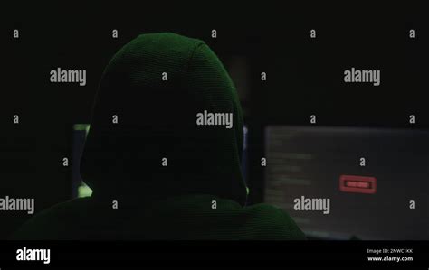 Mysterious Hacker Or Programmer With Hoodie Hacking In A Desolate Room With Green Lights Back
