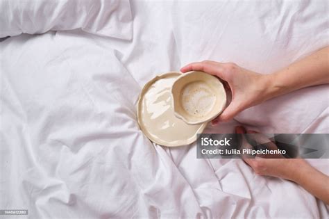 한 여자가 침대에 앉아 커피 한 잔을 들고 있다 흰색 리넨이 있는 침대에 향기로운 커피 한 잔 모닝 커피 컨셉 Comfort Food에 대한 스톡 사진 및 기타 이미지