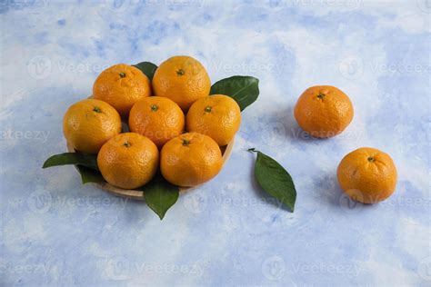 Close Up Photo Of Clementine Mandarins On Wooden Plate Over Blue