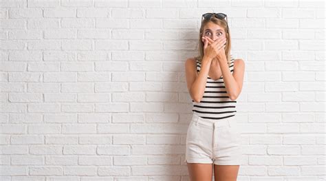 흰색 벽돌 벽 입 실수에 대 한 손으로 다루는 충격 을된 통해 젊은 아름 다운 금발 여자 비밀 개념입니다 가리기에 대한 스톡 사진 및 기타 이미지 Istock