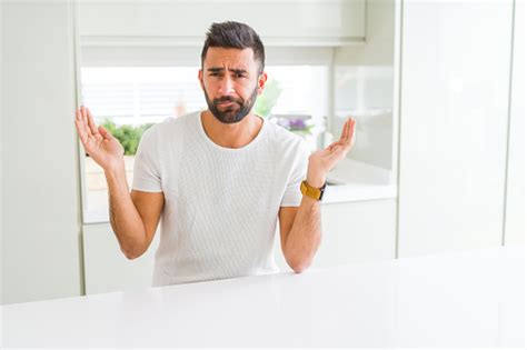 잘 생긴 히스패닉 남자 캐주얼 흰색 티셔츠 집에서 단서와 팔과 손을 제기 와 혼란 표정 의심 개념 T 셔츠에 대한 스톡 사진 및 기타 이미지 Istock