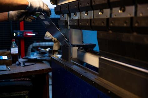 Premium Photo A Workers Gloved Hands Carefully Position A Metal Sheet Into An Industrial Press
