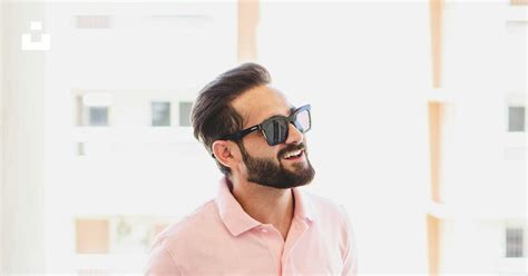 분홍색 드레스 셔츠와 파란색 데님 청바지에 검은 선글라스를 쓴 남자 사진 Unsplash의 무료 미소 이미지