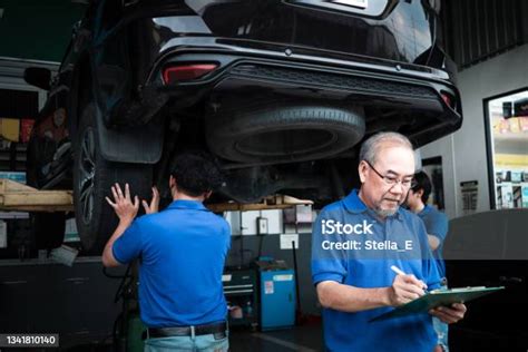 자동차 차고 서비스에서 고객 차의 차체에서 검사하는 두 정비사 차량 수리 서비스 상점 개념에서 두 정비사 검사 휠동안 차량 수리