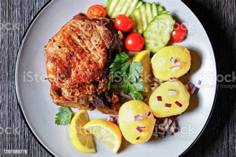 구운 돼지고기 카르보나데 삶은 감자를 곁들인 돼지고기 커틀릿 나무 테이블에 접시에 얇게 썬 오이와 레몬 위에에 대한 스톡 사진 및 기타 이미지 Istock