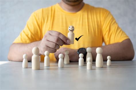 The Human Hand Picking Up One Smile Wooden Person From Group Of Many