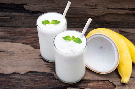 바나나 코코넛 스무디 화이트 과일 주스 밀크 쉐이크 블렌드 음료 건강 한 고 단백 유리 음료 에피소드 아침 나무 배경에서 맛 있는 맛 건강한 생활방식에 대한 스톡 사진 및