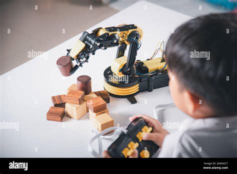 Happy Asian Little Boy Using Remote Control Playing Robotic Machine Arm